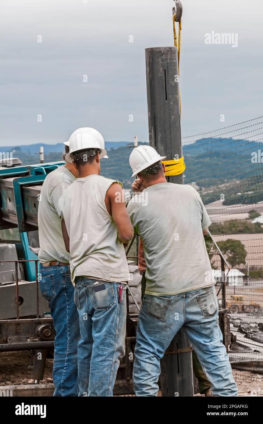 Four workers assist on drilling a methane gas well in an active ...