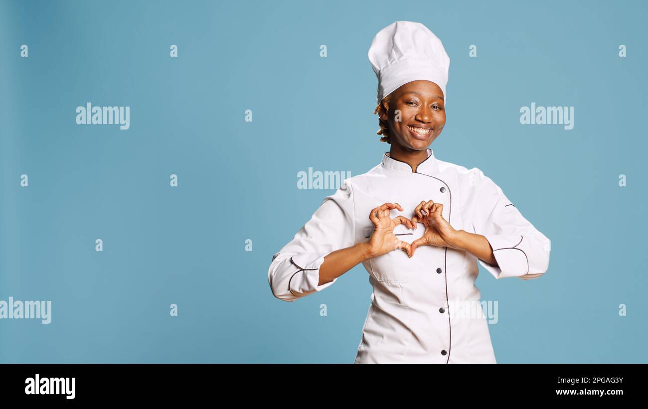 Female cook showing heart shaped symbol on camera, expressing romantic ...