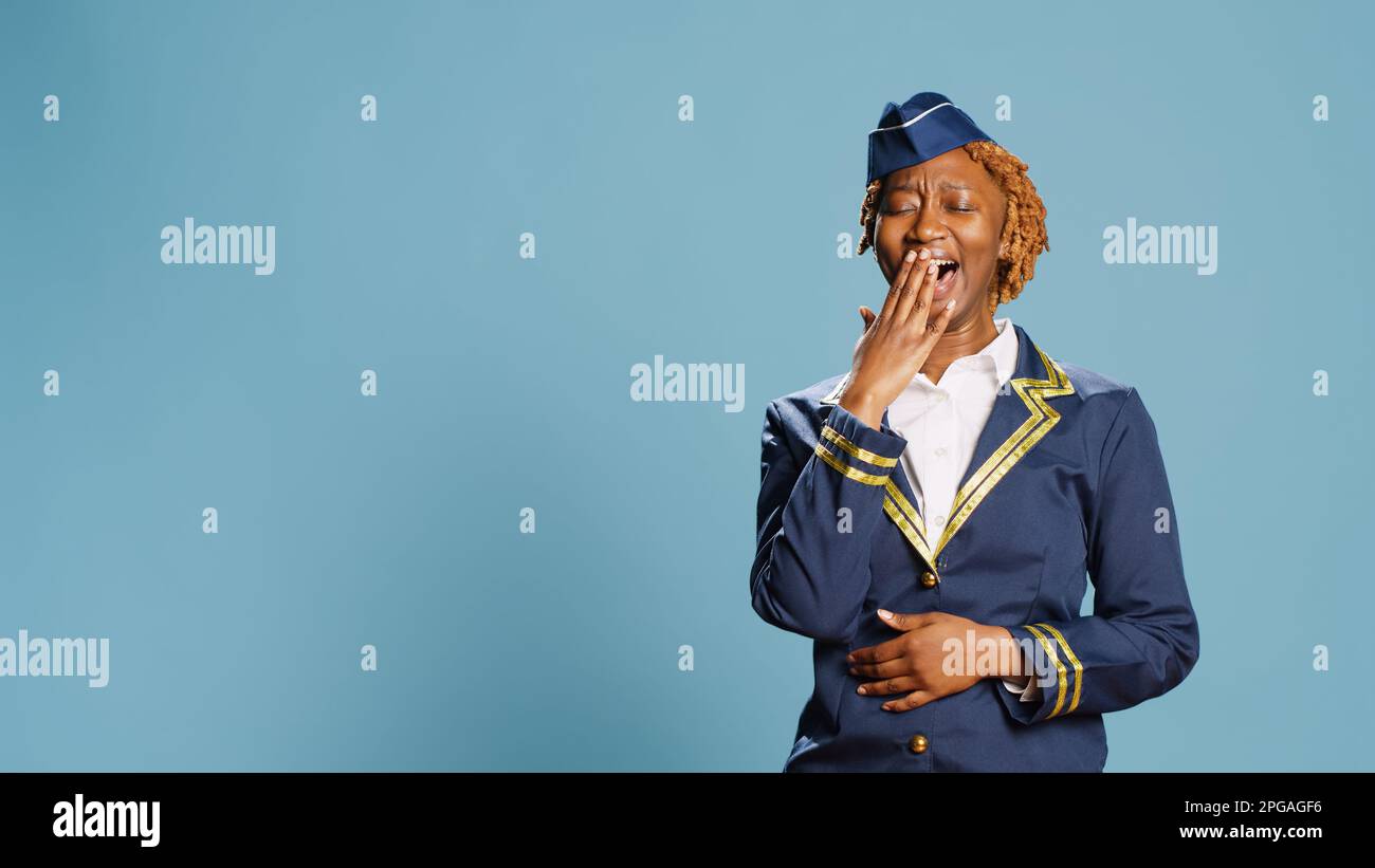 African american stewardess yawning in studio, being tired and worn out ...