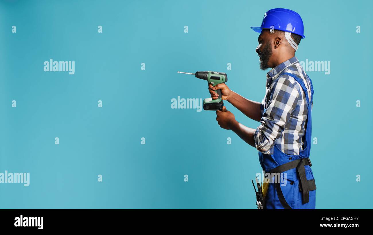 Male builder using power drill instrument on wall, drilling nails with ...
