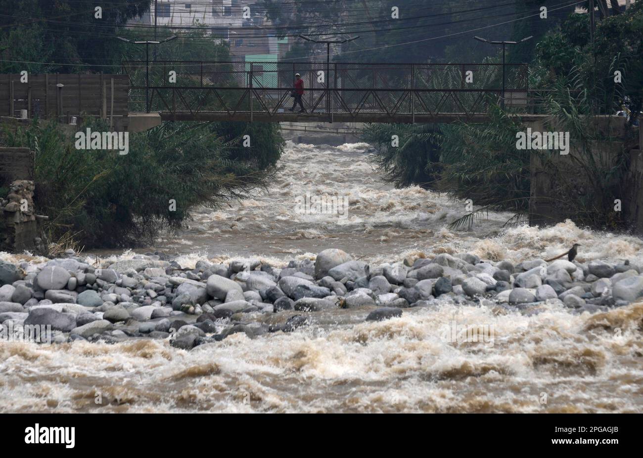 A woman walks on a bridge over the Rimac River, a day ahead of World ...