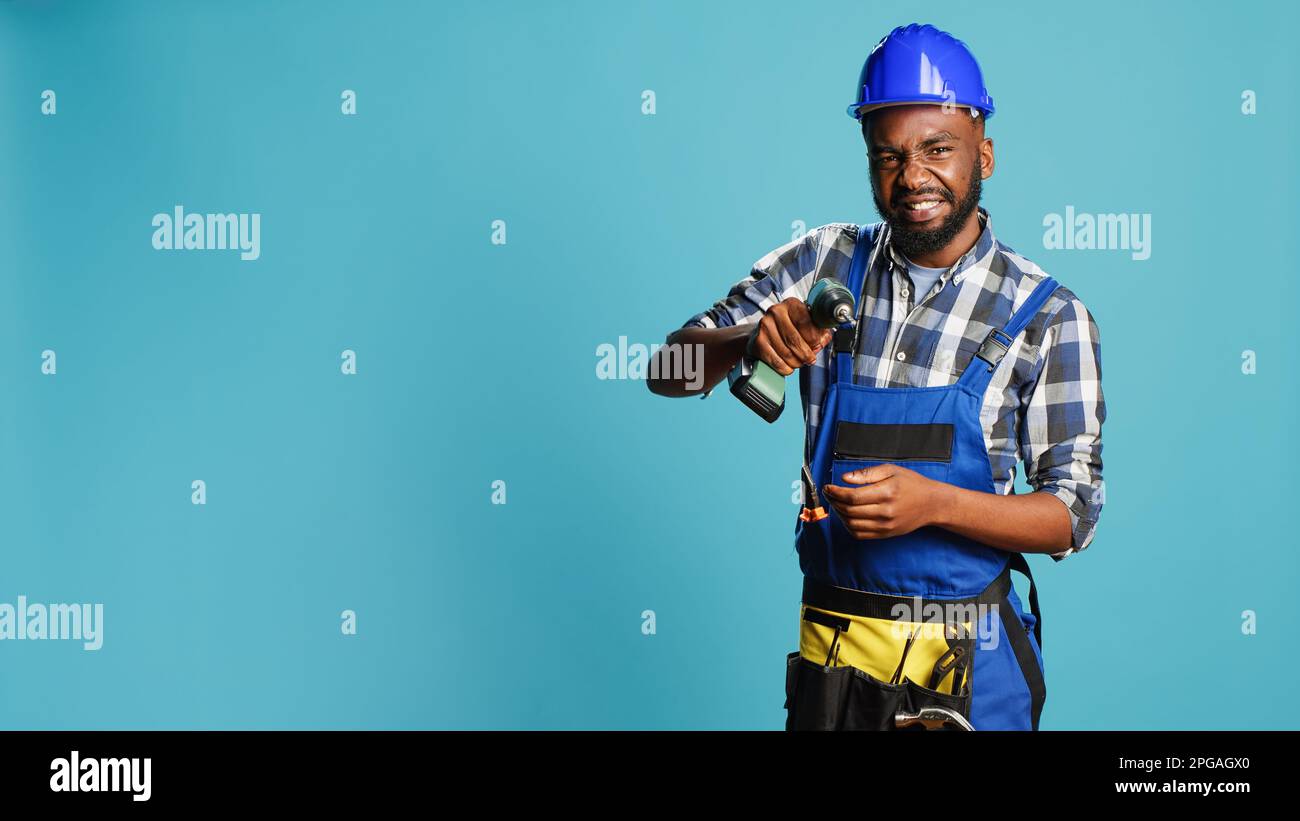 Young repairman using power drill gun on wall, drilling nails with ...