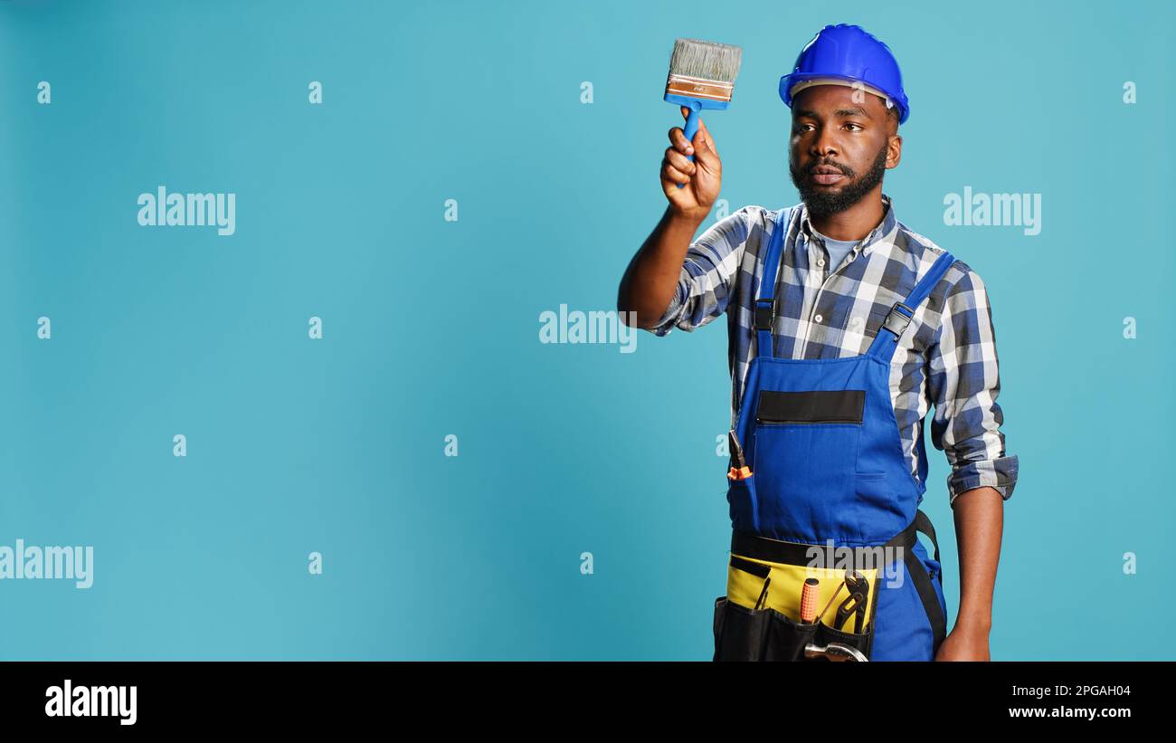 African american man painting walls with brush in studio, using ...