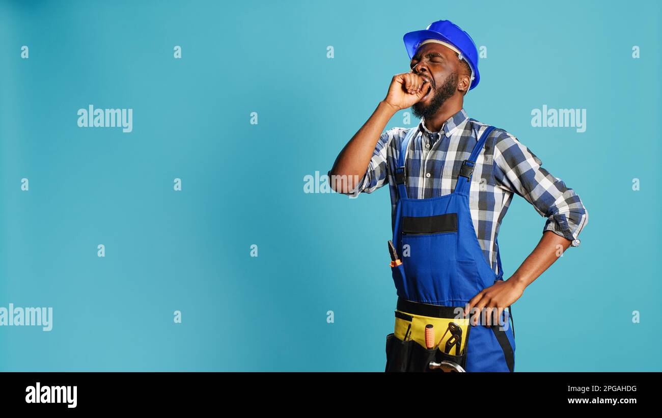 Male builder yawning on camera feeling worn out, man dressed in ...