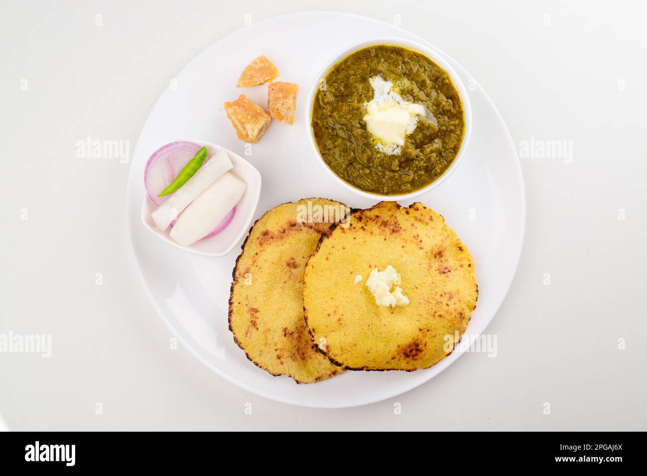 Top view of sarson ka saag with makki ki roti in plate on white ...
