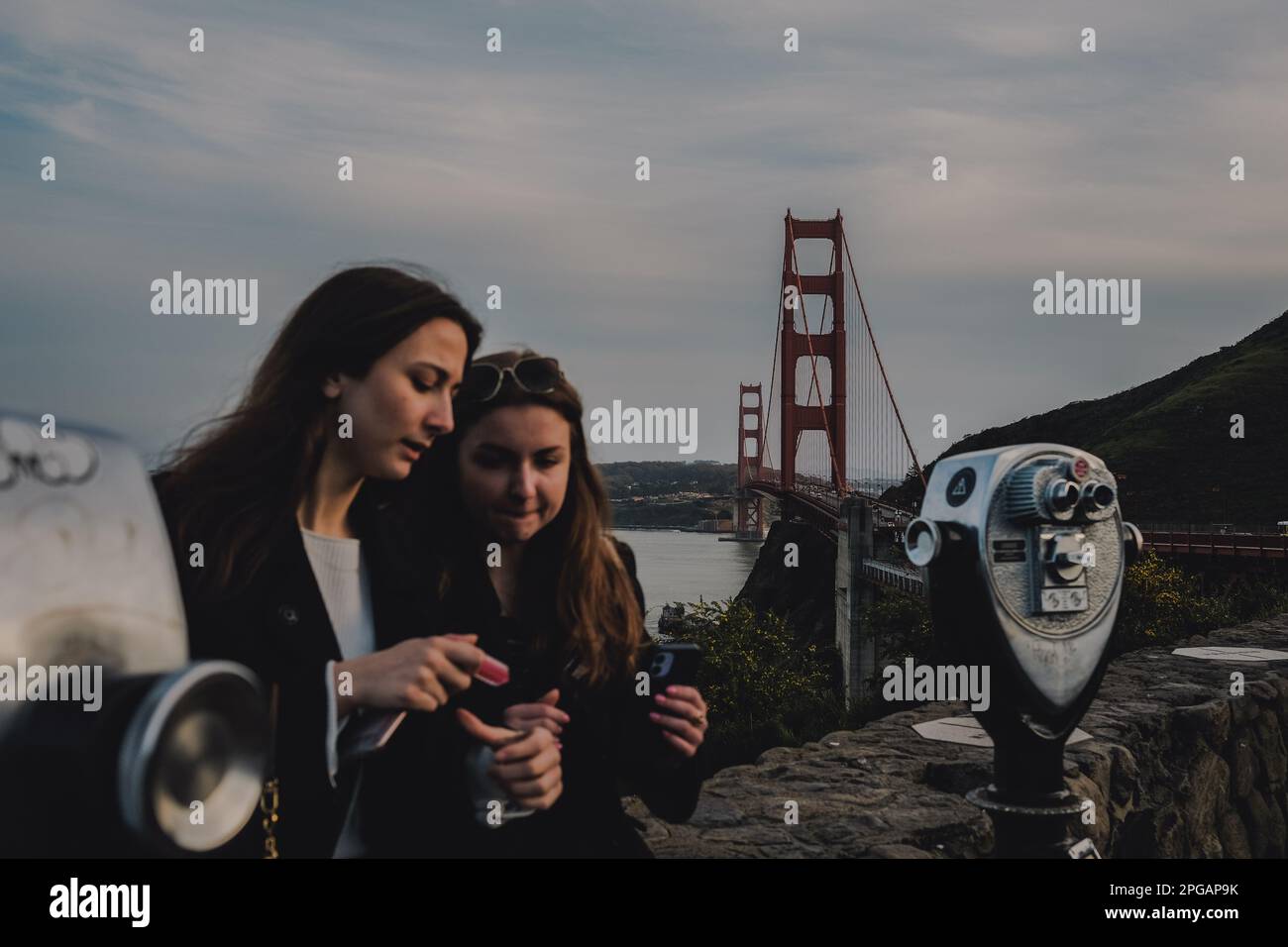 Friends take a photo with the Golden Gate Bridge in the background. The ...