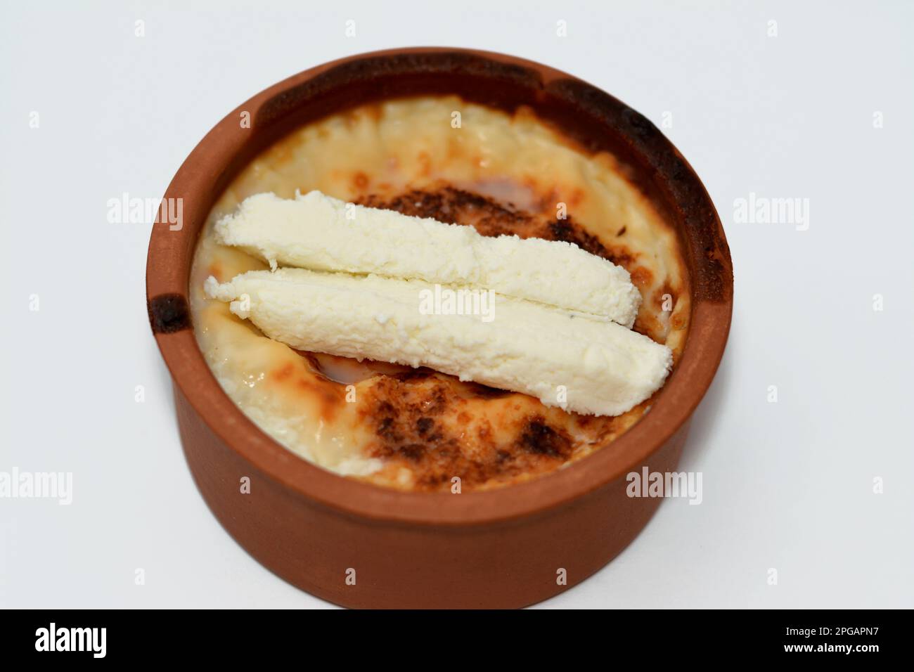 Rice pudding pottery casserole topped with milk cream, rice, corn flour ...