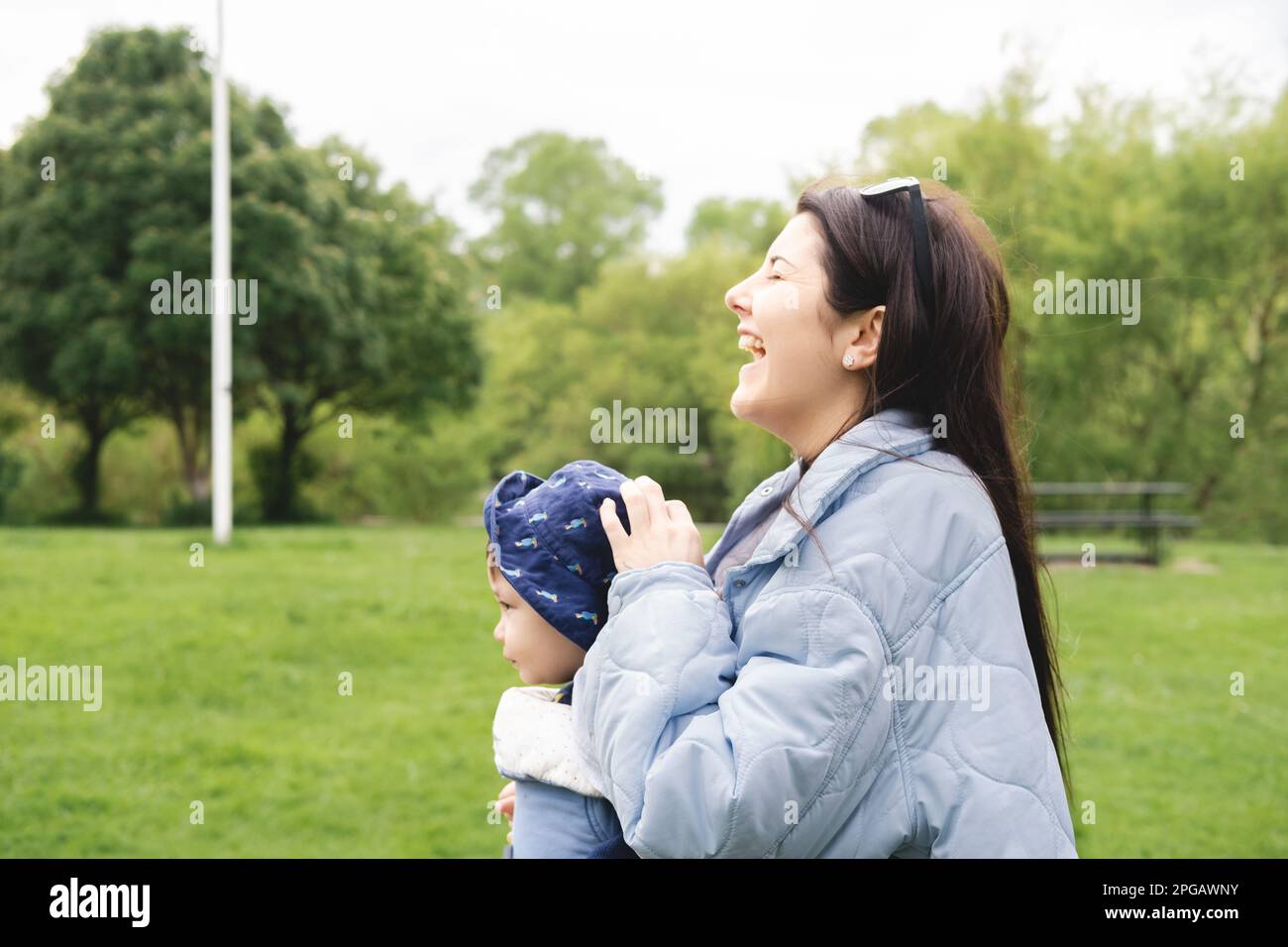 A mother laughing out loudly and carrying her male infant with a baby ...