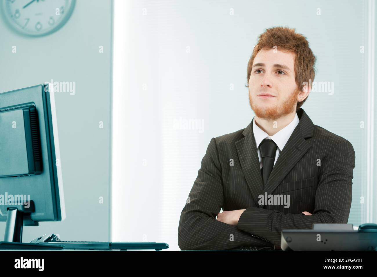 Young clerk in an office looks up thinking or dreaming. Is he planning ...