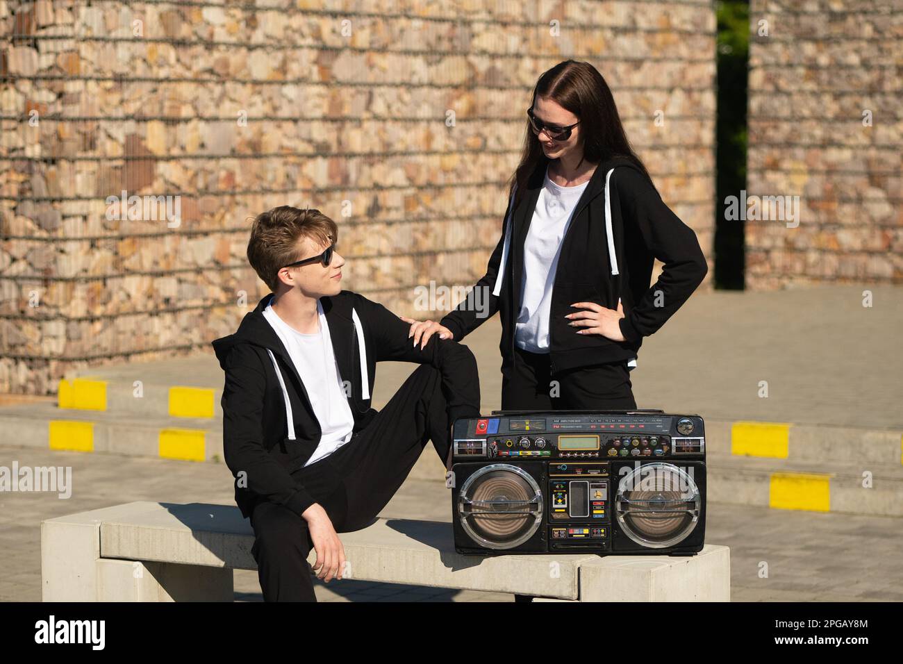 A couple of teenagers in black tracksuits. A boy and a girl on a walk ...