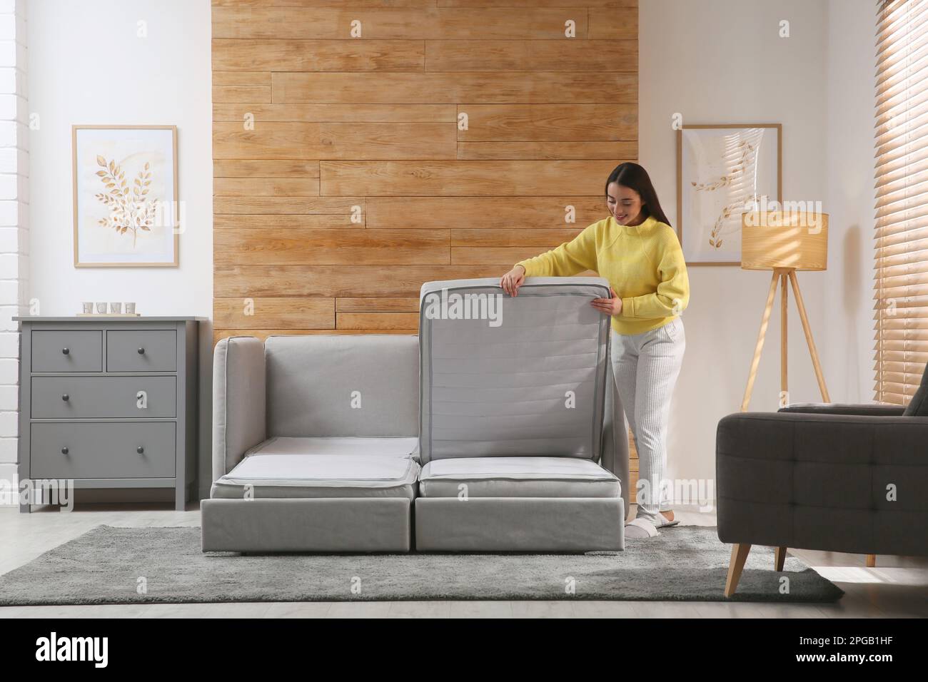 Young woman unfolding sofa into a bed in room. Modern interior Stock ...