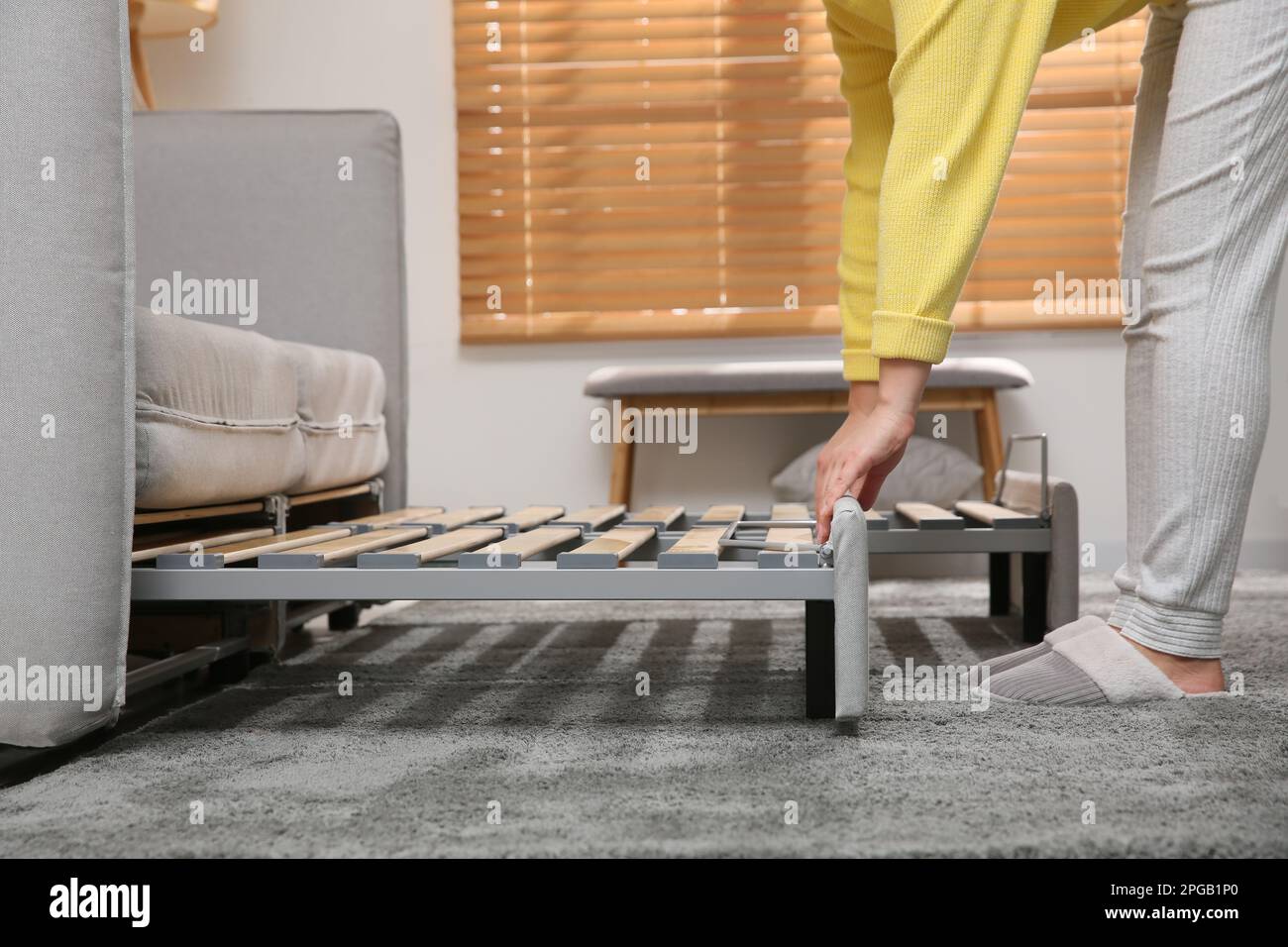 Young woman unfolding sofa into a bed in room, closeup. Modern interior ...