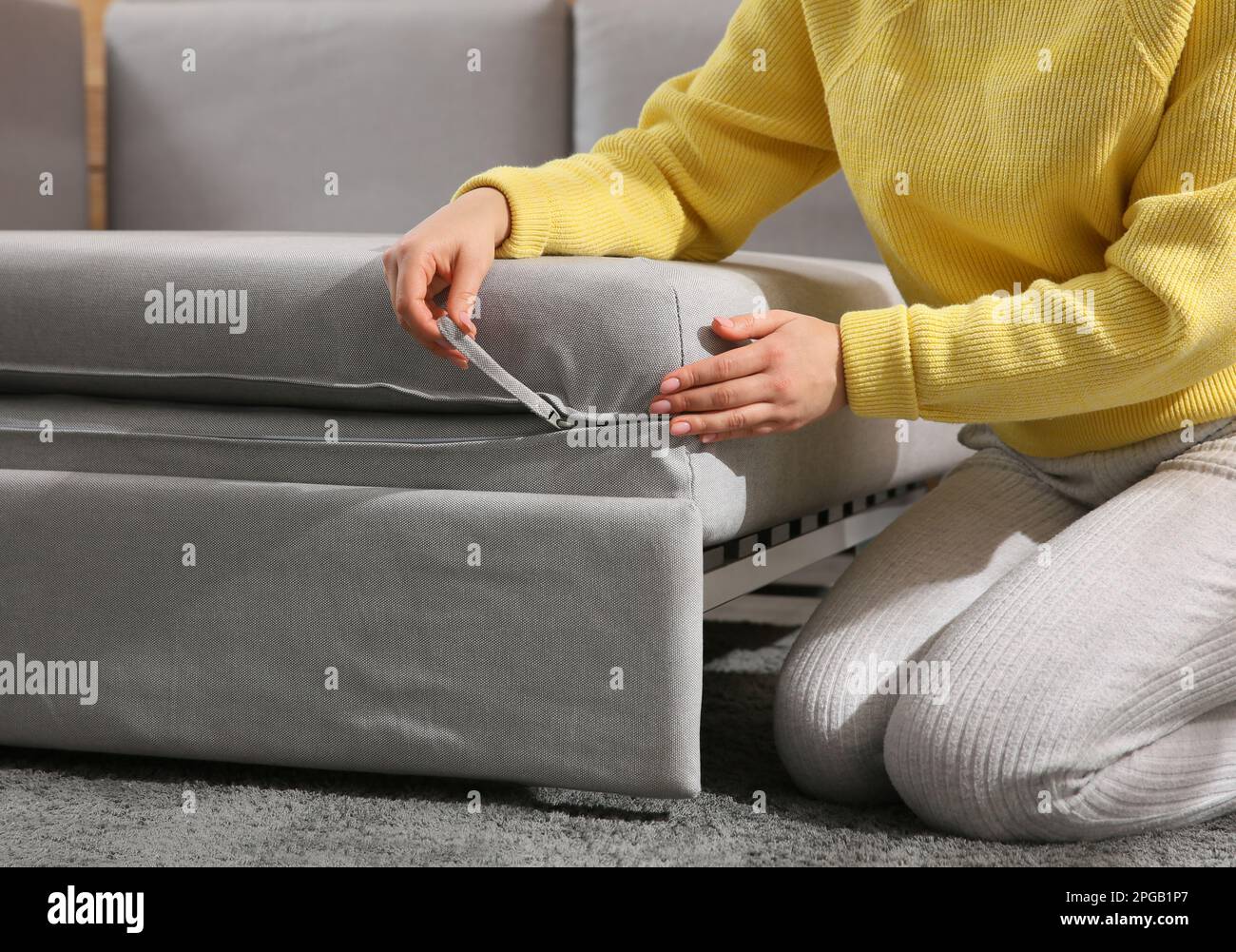 Young woman unfolding sofa into a bed in room, closeup. Modern interior ...