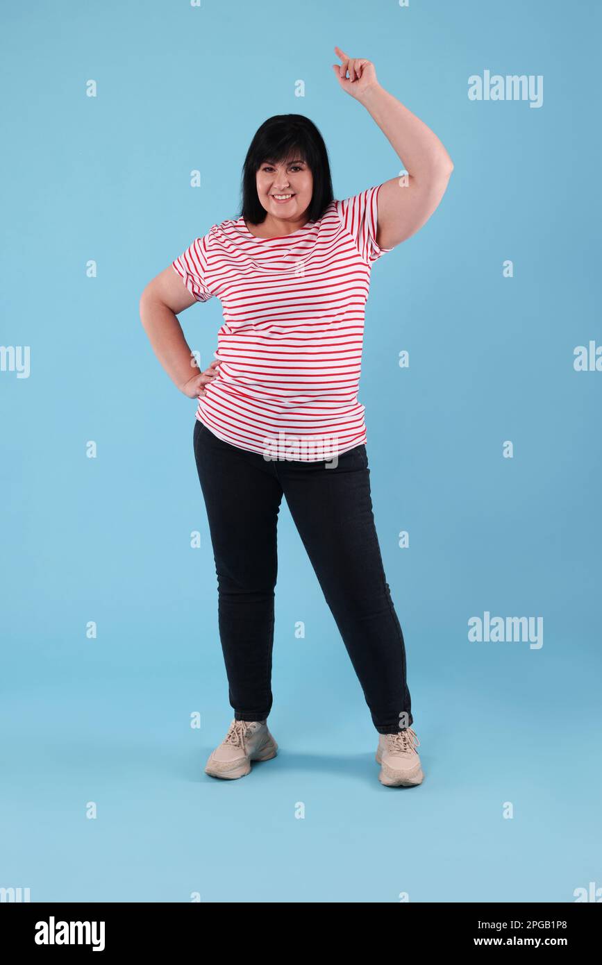 Beautiful overweight mature woman with charming smile on turquoise ...