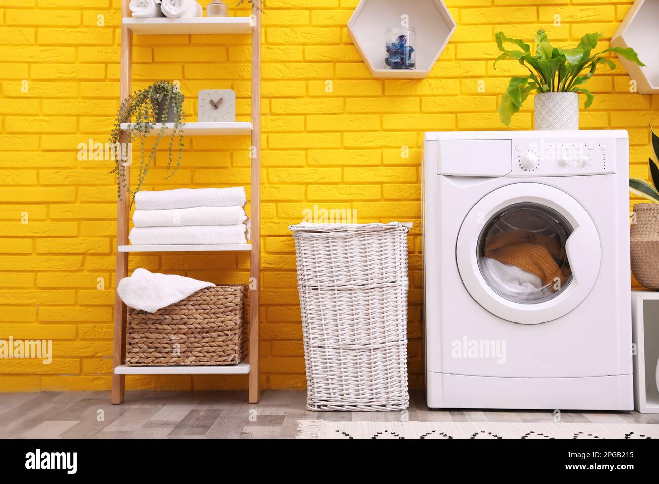Laundry room interior with modern washing machine near yellow brick ...