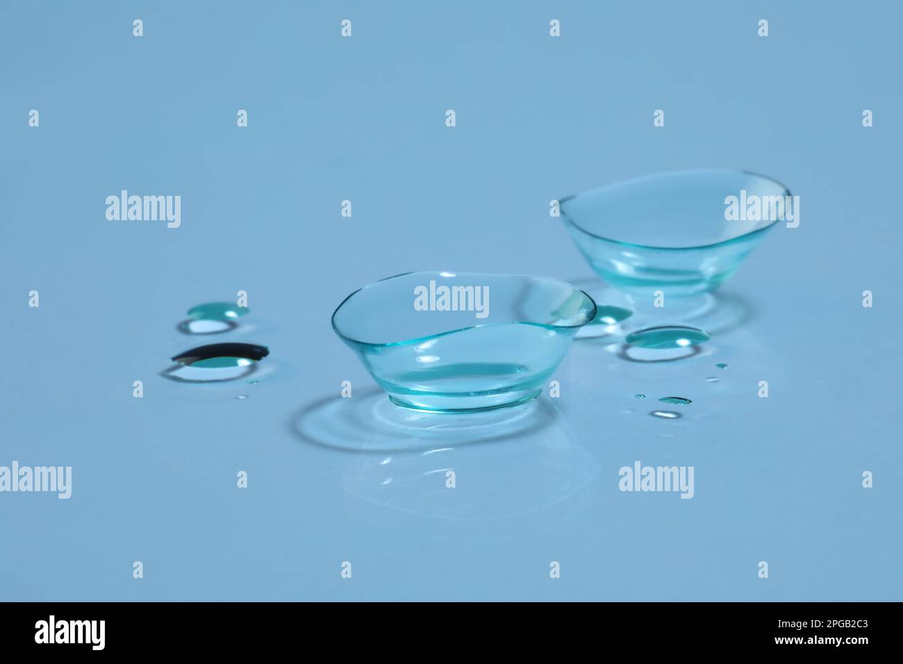 Contact lenses and drops of water on light blue background Stock Photo ...