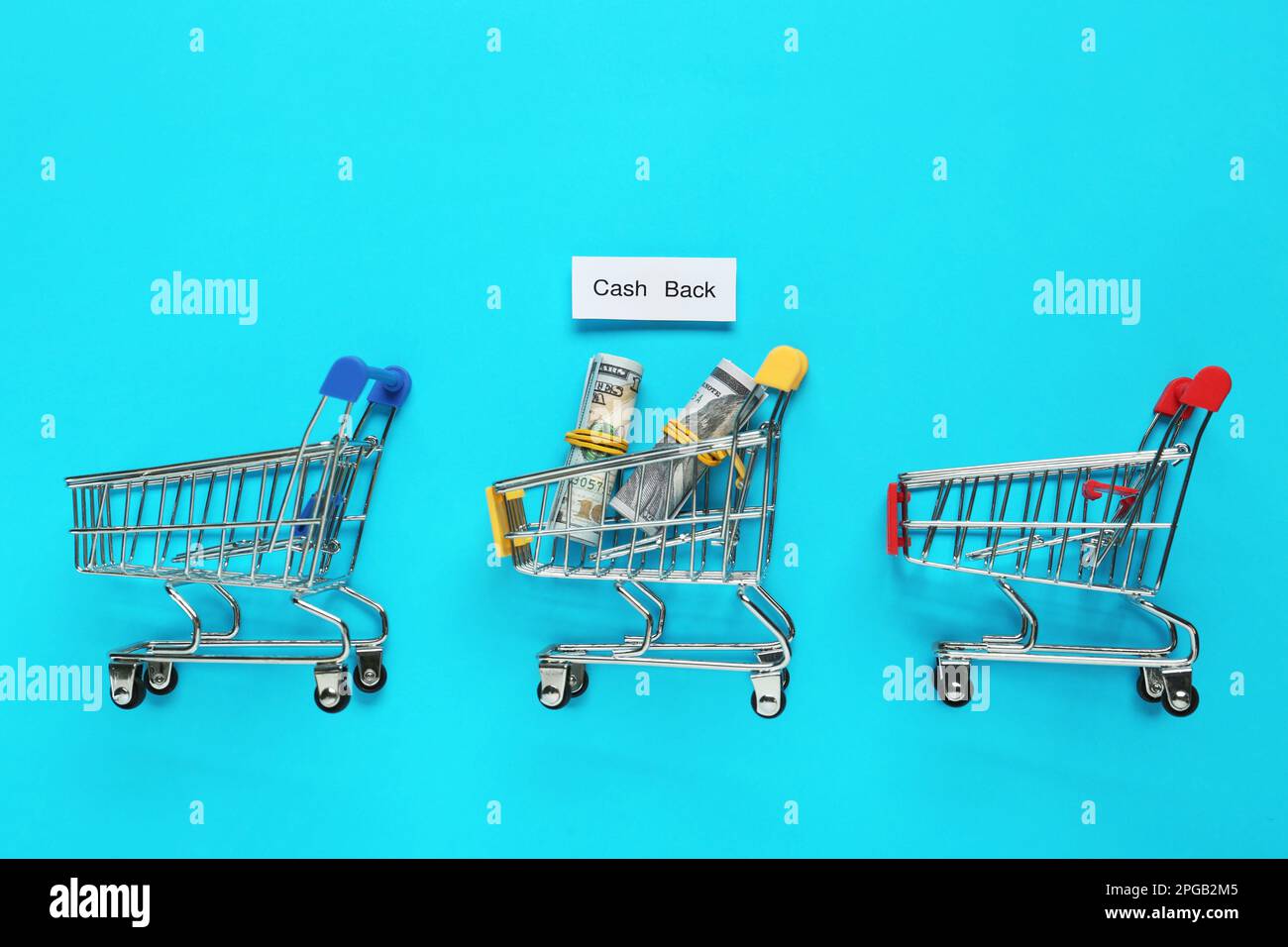 Card with word Cashback, rolled dollar banknotes and shopping carts on ...