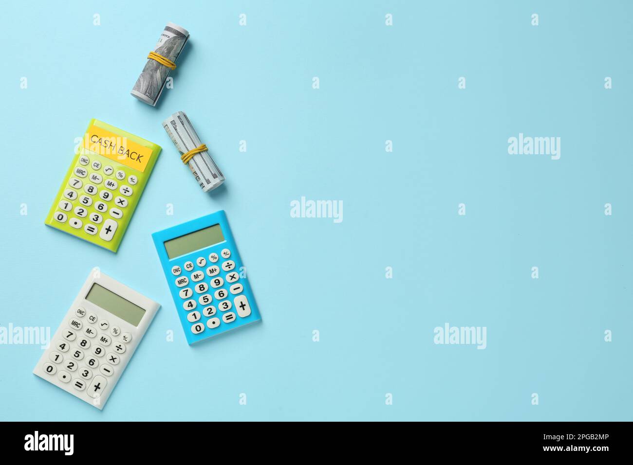 Different calculators and rolled dollar banknotes on light blue ...
