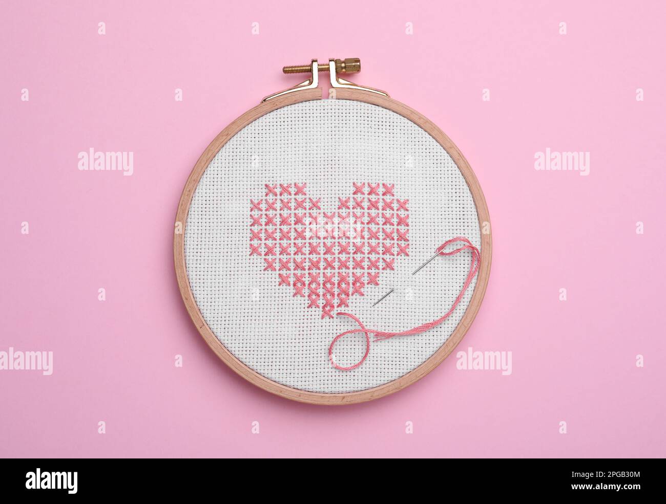 Canvas with embroidered heart and needle in hoop on pink background ...