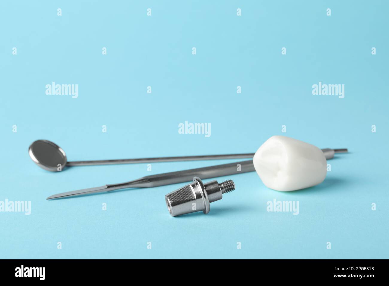 Abutment and crown of dental implant near medical tools on light blue ...