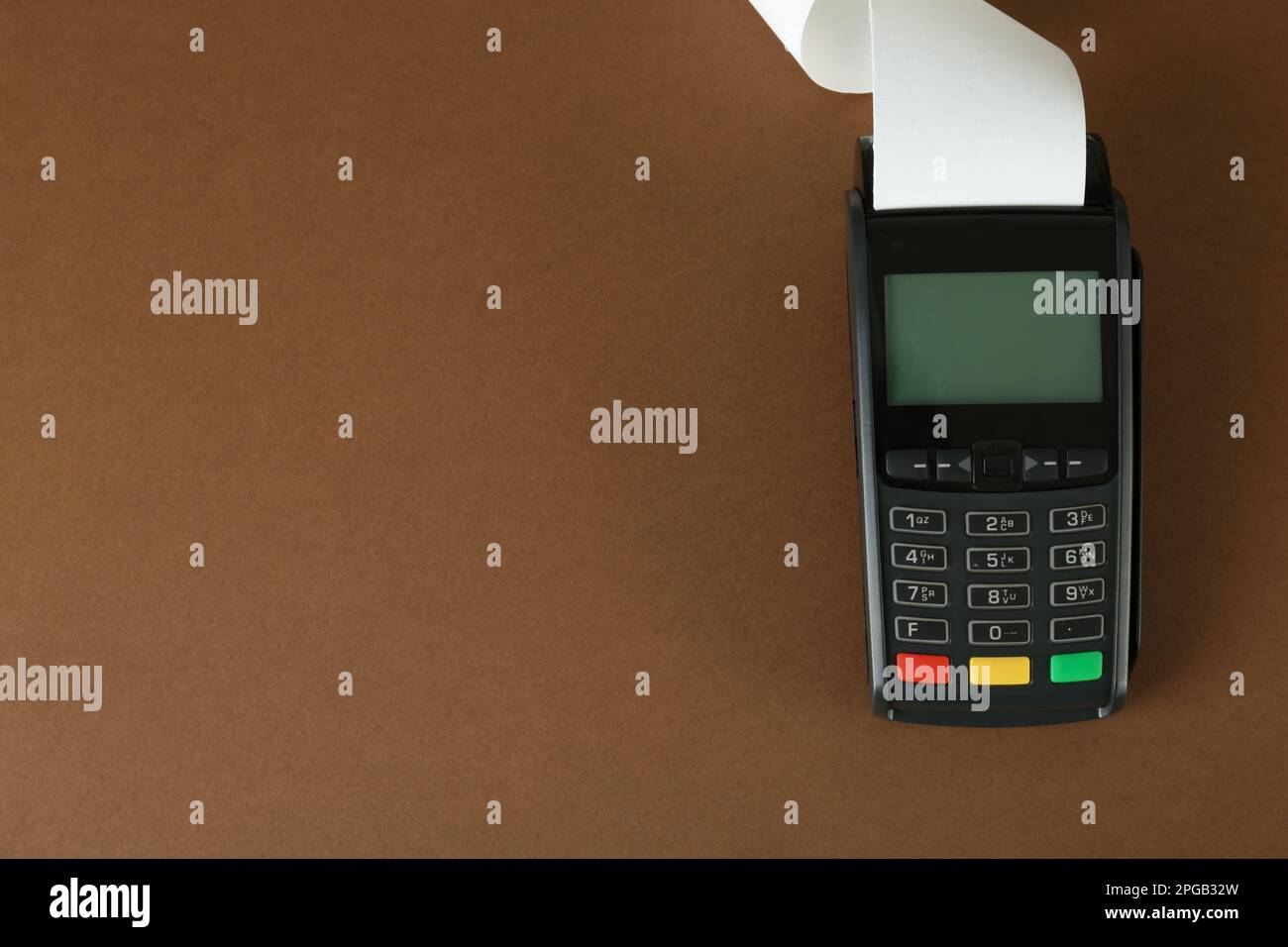 New modern payment terminal with blank paper bill on brown background ...