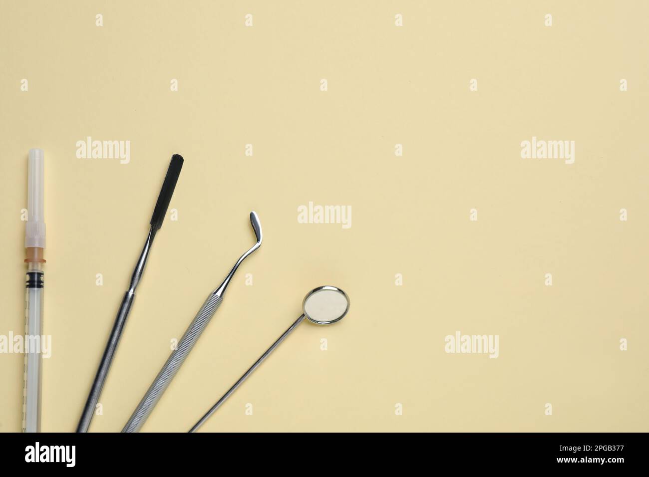 Set of dentist's tools and syringe on pale yellow background, flat lay ...