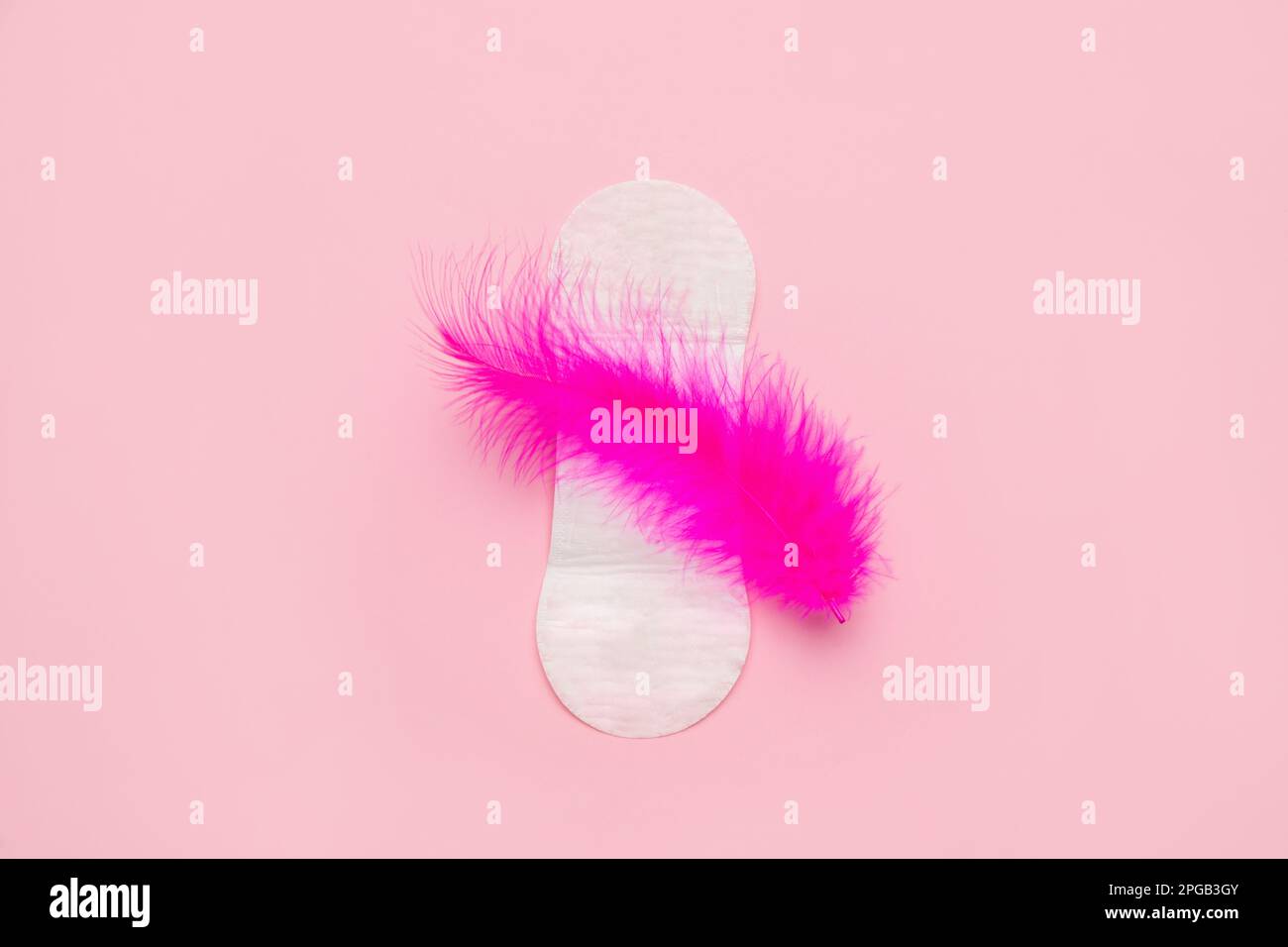 Sanitary pad with feather on pink background, top view. Menstrual cycle ...
