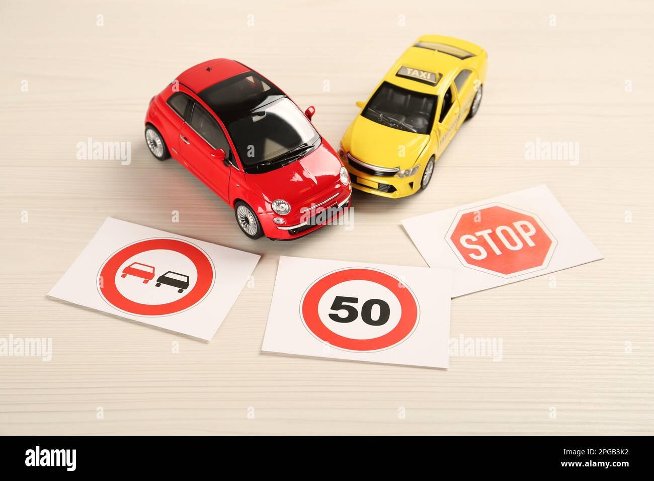 Cards with different road signs and toy cars on white wooden table ...