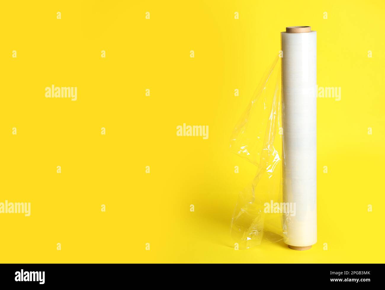 Roll of plastic stretch wrap film on yellow background, space for text ...