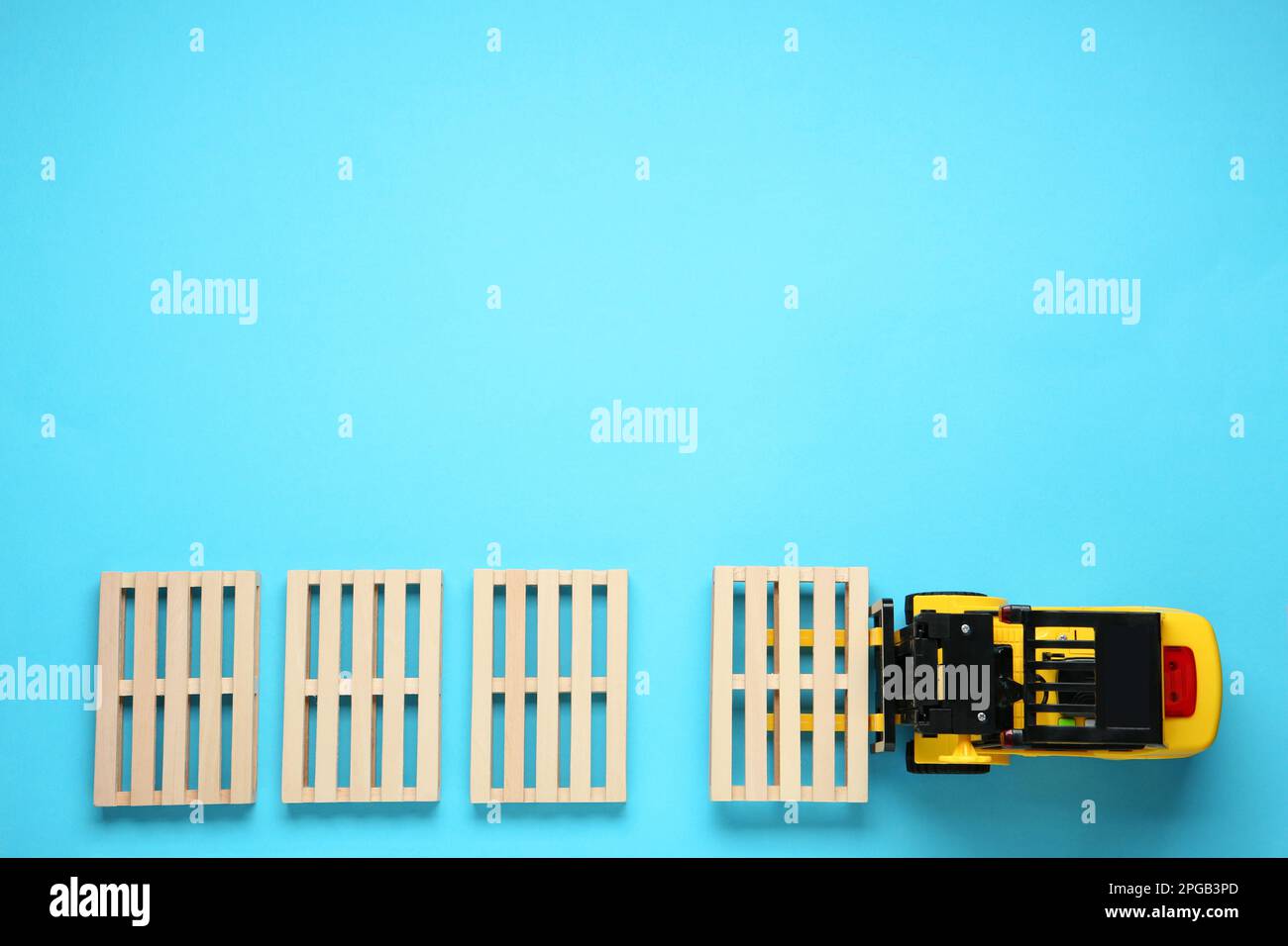 Toy forklift and wooden pallets on light blue background, flat lay ...