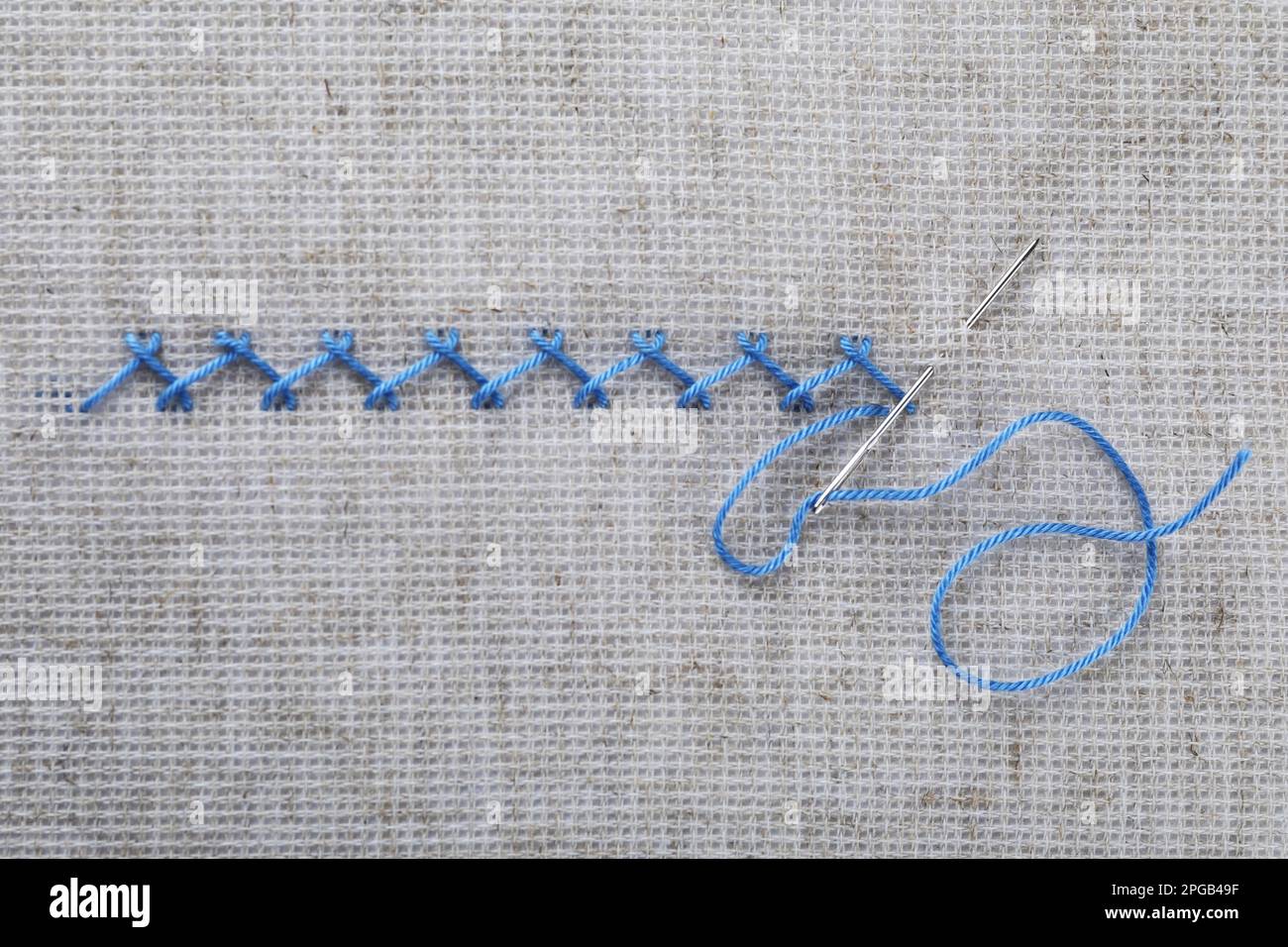 Embroidery stitches made with light blue thread and needle on canvas ...