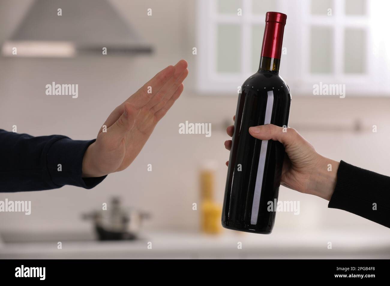 Man refusing to drink red wine in kitchen, closeup. Alcohol addiction ...