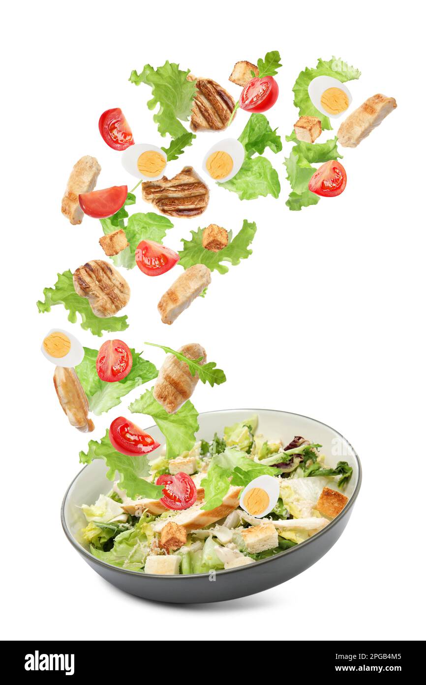 Tasty ingredients for Caesar salad falling into plate on white ...