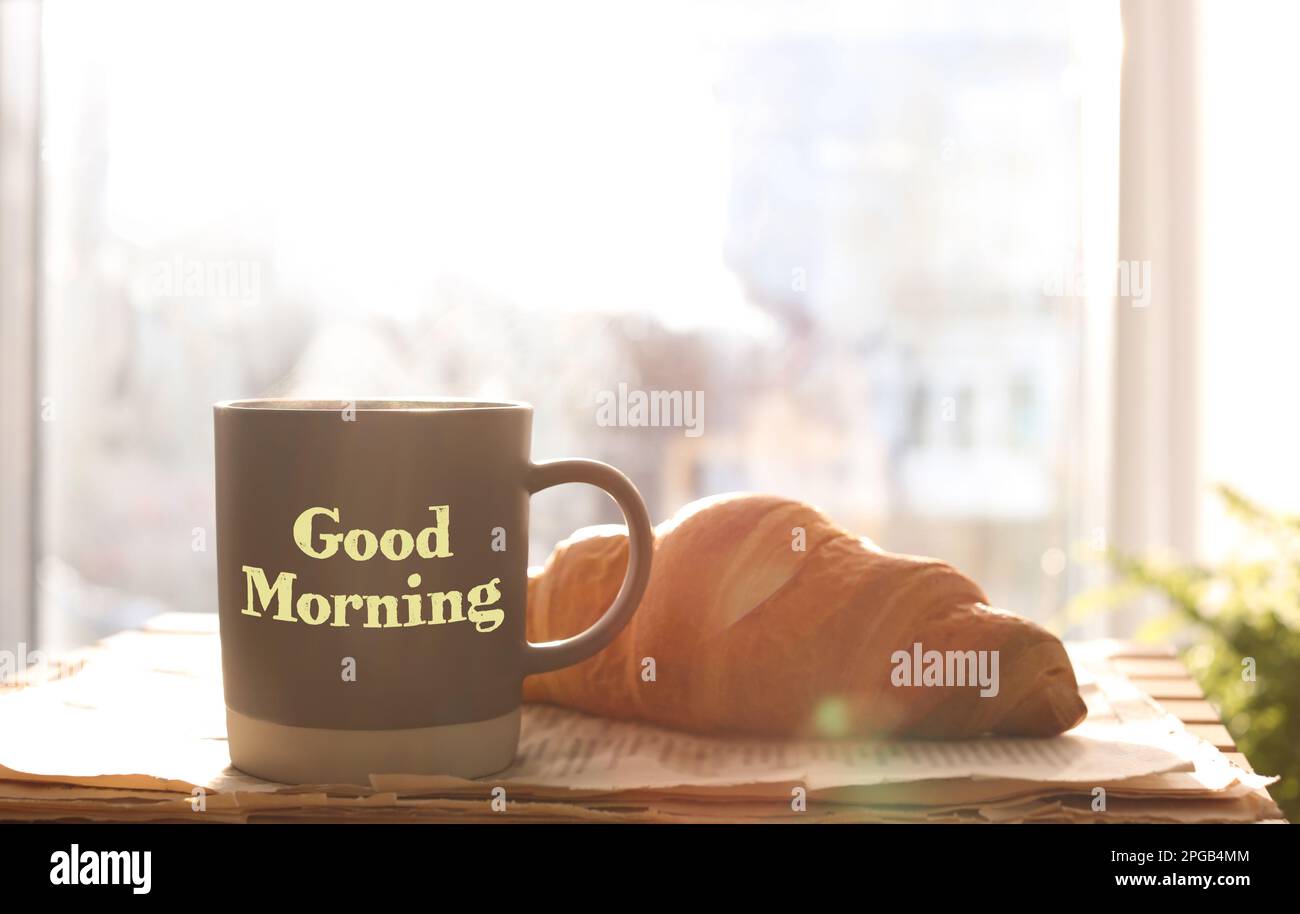 Good Morning. Delicious coffee, newspaper and croissant near window ...