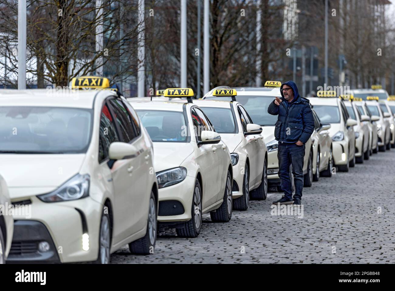 Many taxis queuing up, waiting in line at the taxi stand, man talking ...