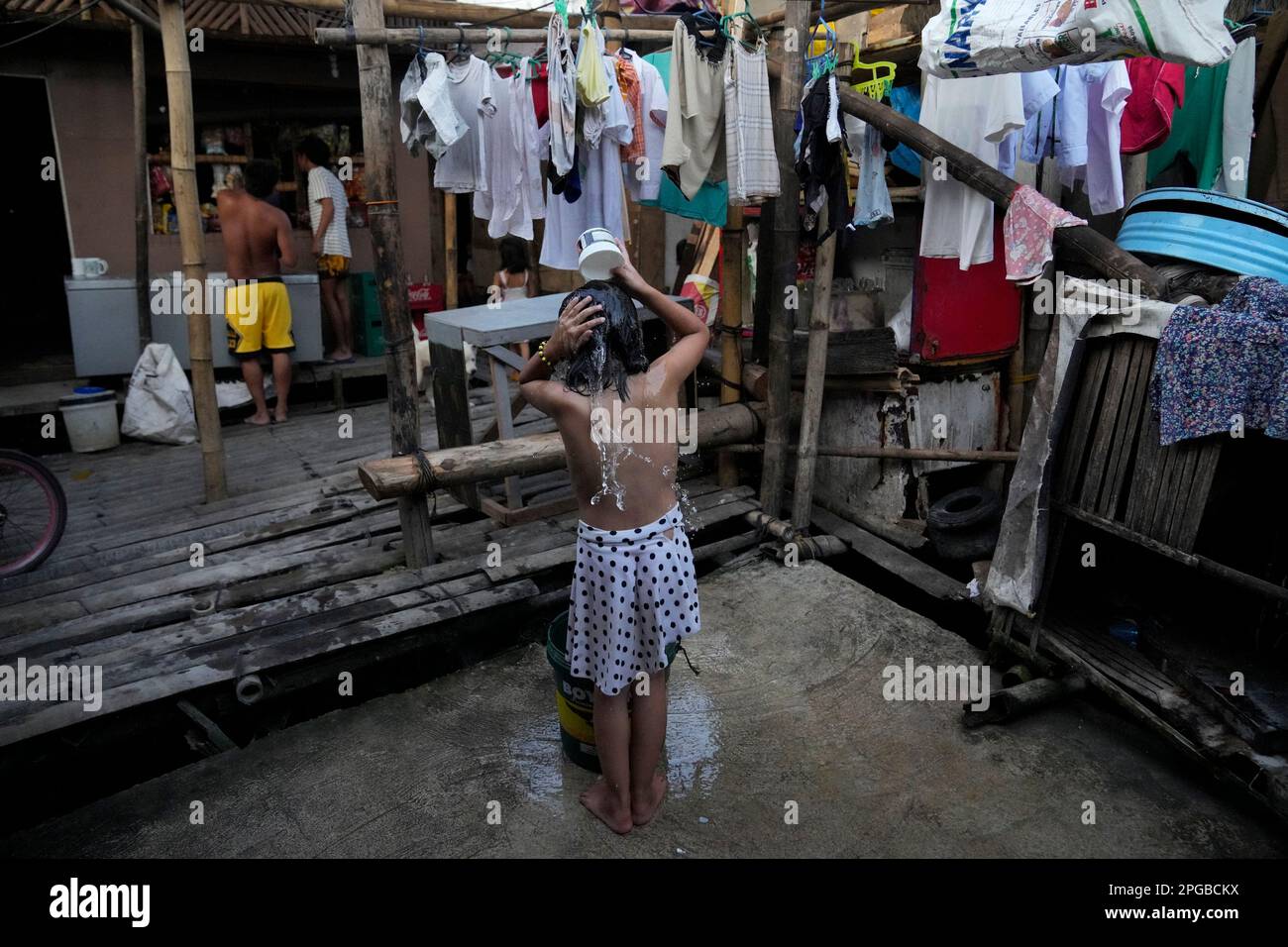 A girl takes a bath near a manual water pump at a slum area in ...
