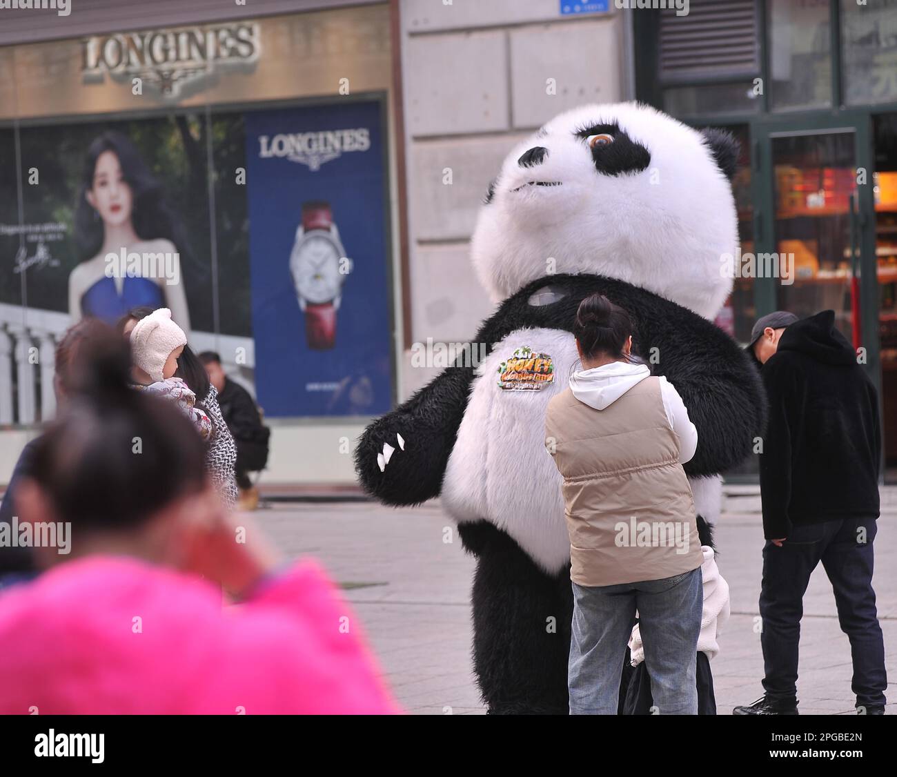 People interact with a giant panda acted by staff from an amusement ...