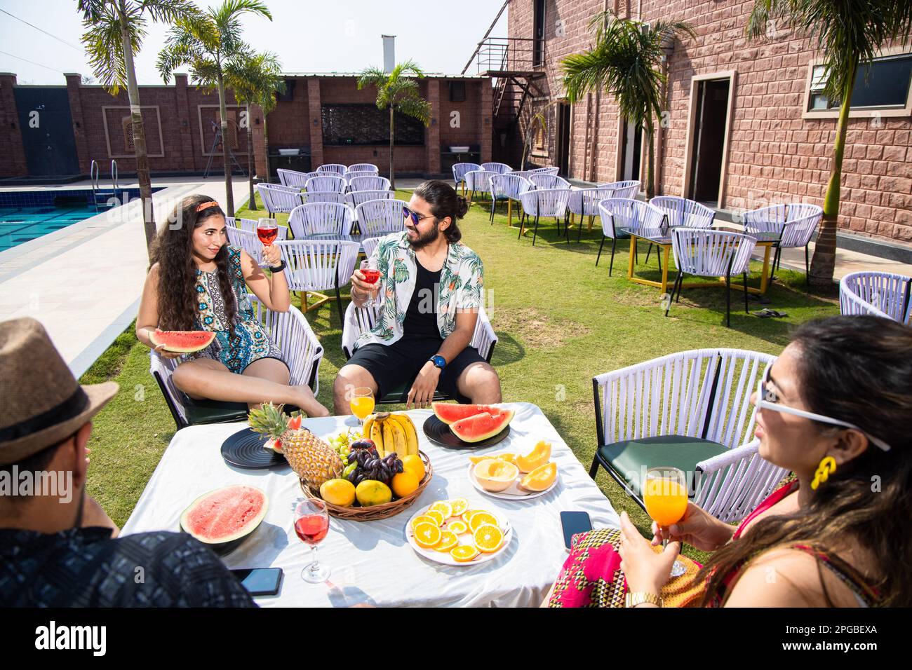 Group of indian friends enjoy fruits and juice at outdoors summer party ...