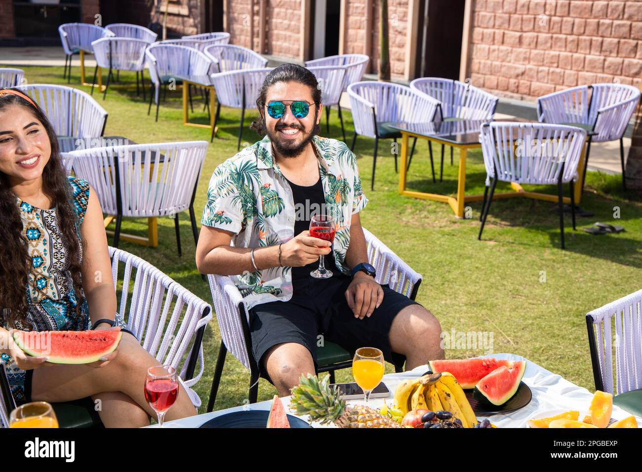 Young indian man wearing sunglasses holding glass of fresh juice in hot ...
