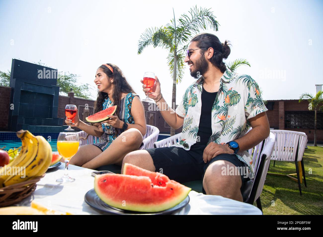 Happy indian friends enjoying watermelon together outdoor resort or ...