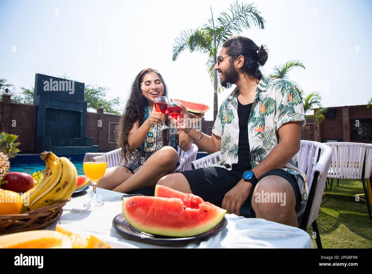 Happy indian friends enjoying watermelon together outdoor resort or ...