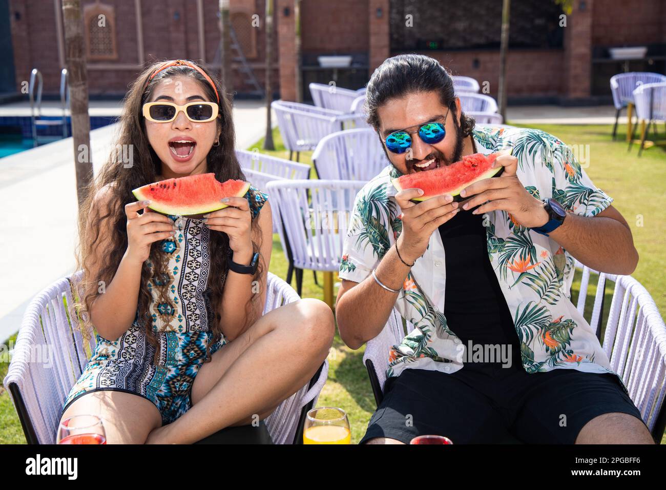 Happy indian friends enjoying watermelon together outdoor resort or ...