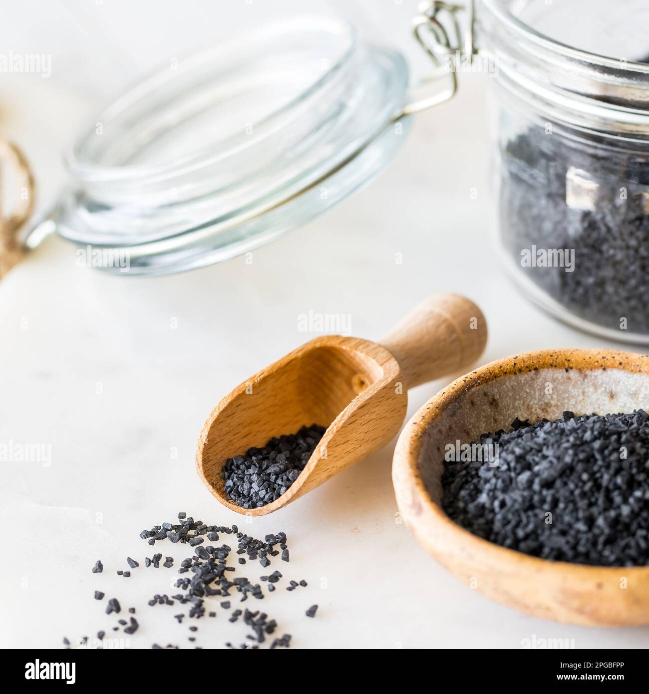 Black Hawaiian rock salt in a jar, bowl and small wooden scoop Stock ...