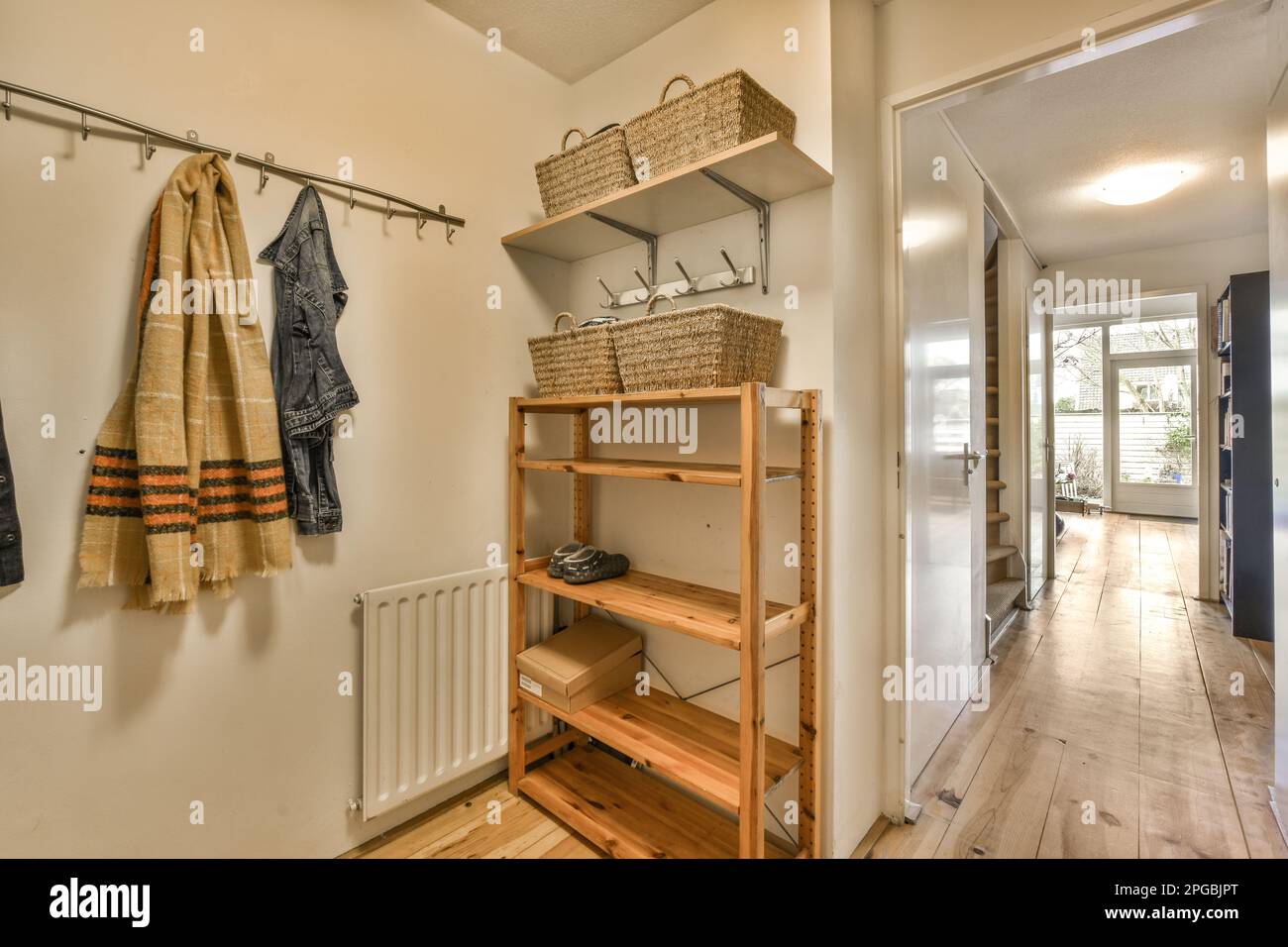 the inside of a house with clothes hanging on hooks, and a shelf filled ...