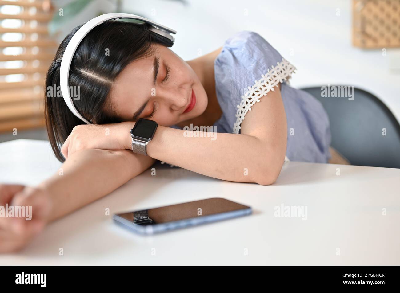 Relaxed young Asian female listening to music through her headphones ...