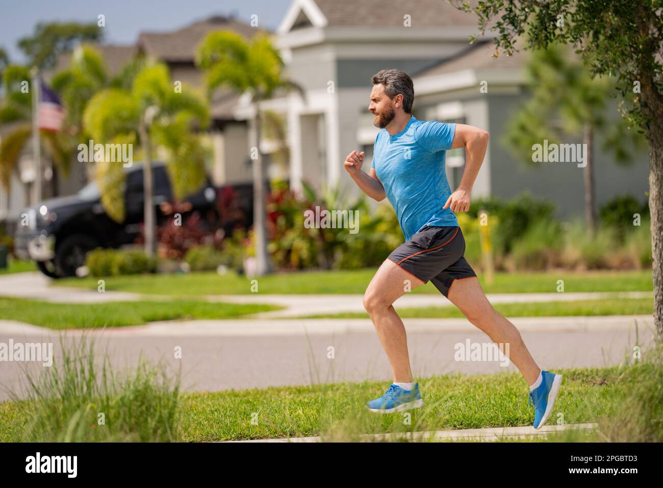 Man running on street in neighborhood. Handsome athlete running in the ...