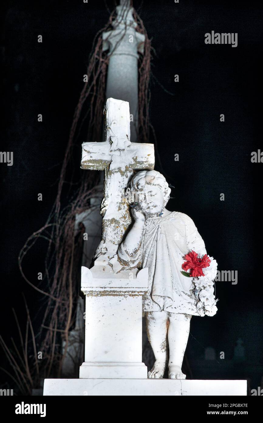 A white stone cross with an angel figure affixed to it, standing ...