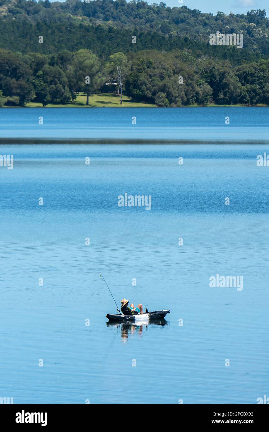 Fisherman relaxing and fishing from a kayak on Lake Tinaroo, a popular ...