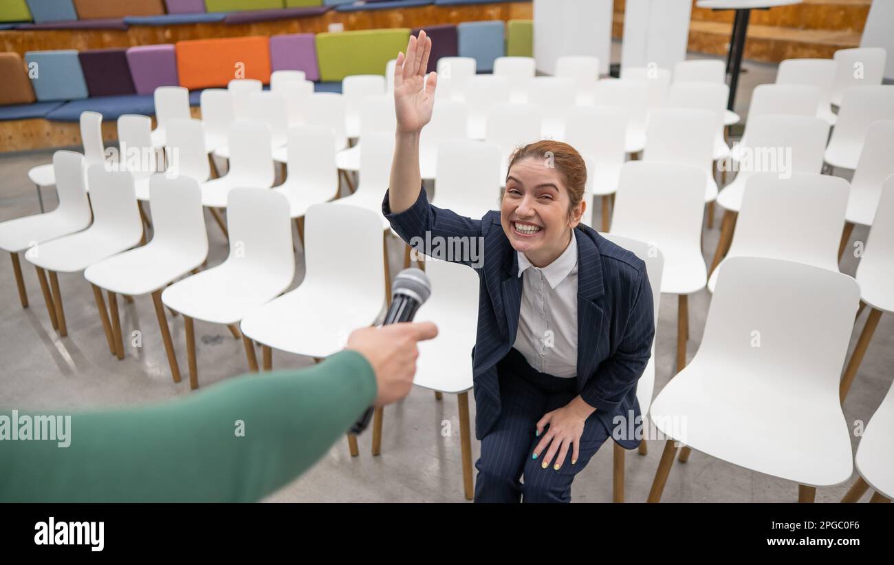 A red-haired Caucasian business woman sits in the front row in an empty ...