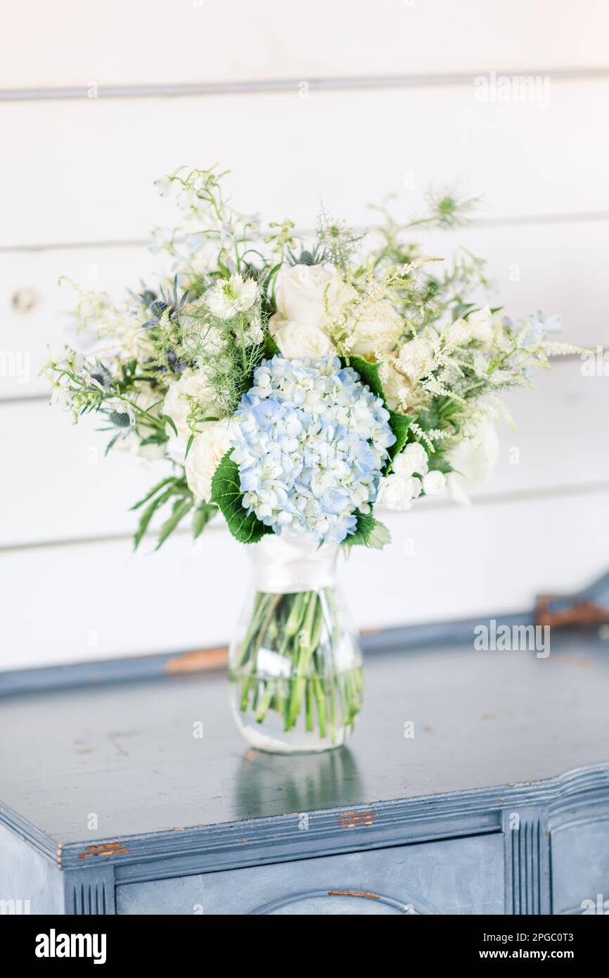 A vertical image of a tall glass vase with white flowers placed inside ...